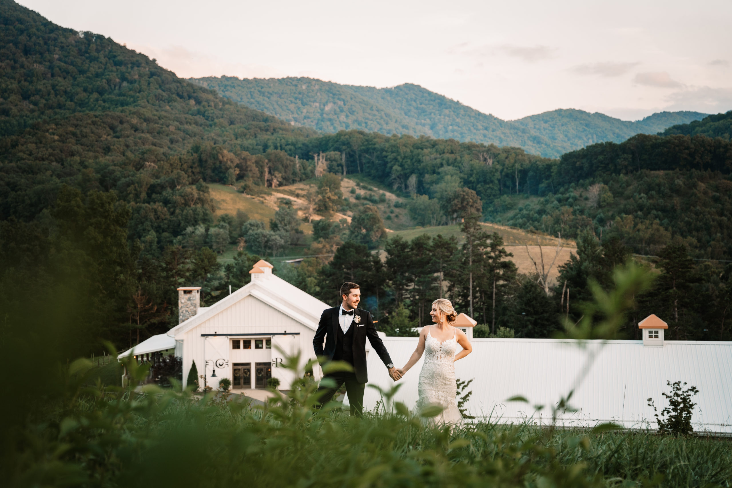 Couple walks with mountains and chestnut ridge wedding venue behind ...