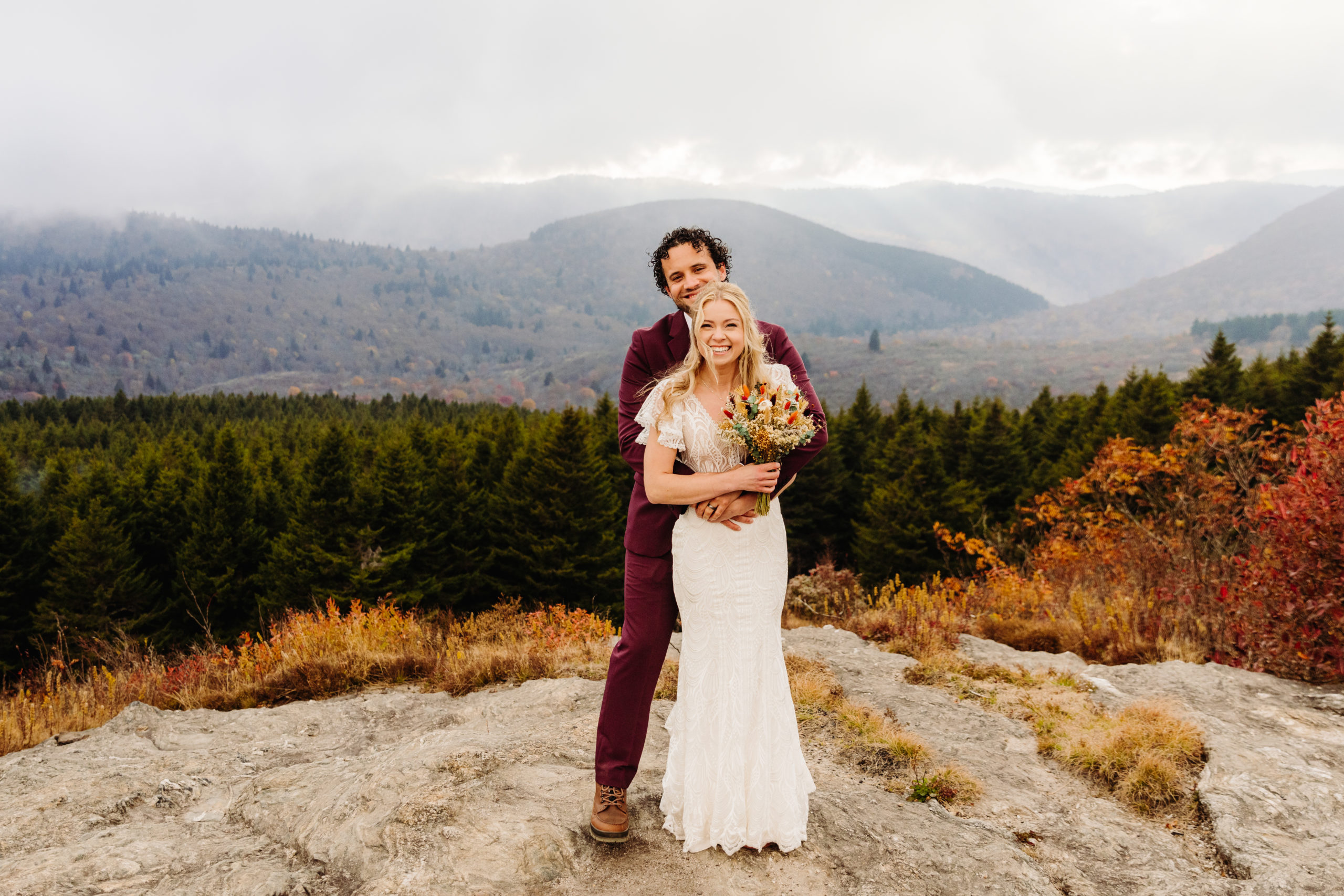 Happy bride laughs as groom hugs from behind ~ Elope Outdoors