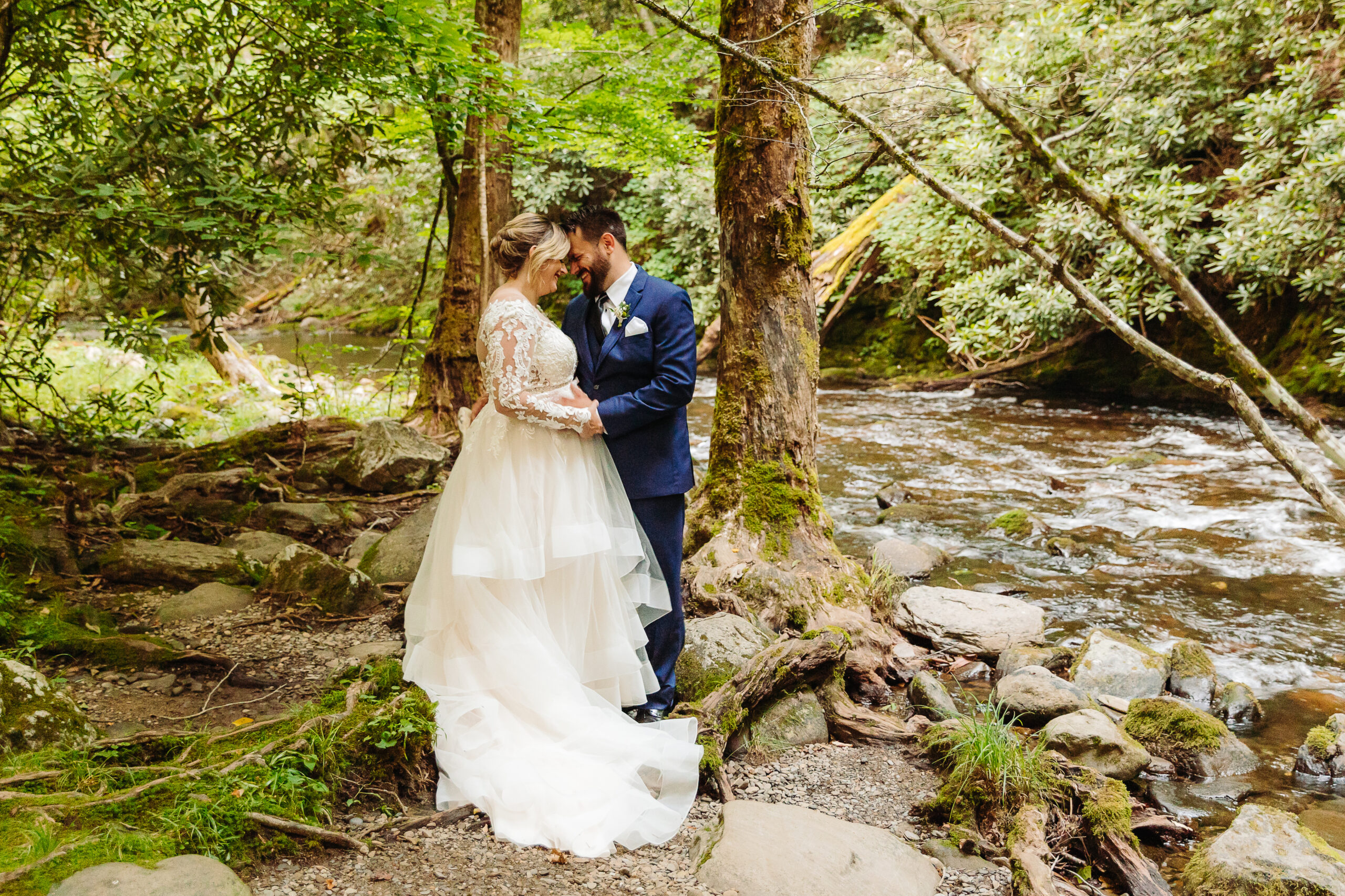 Couple poses by river Cataloochee Valley elopement ~ Elope Outdoors